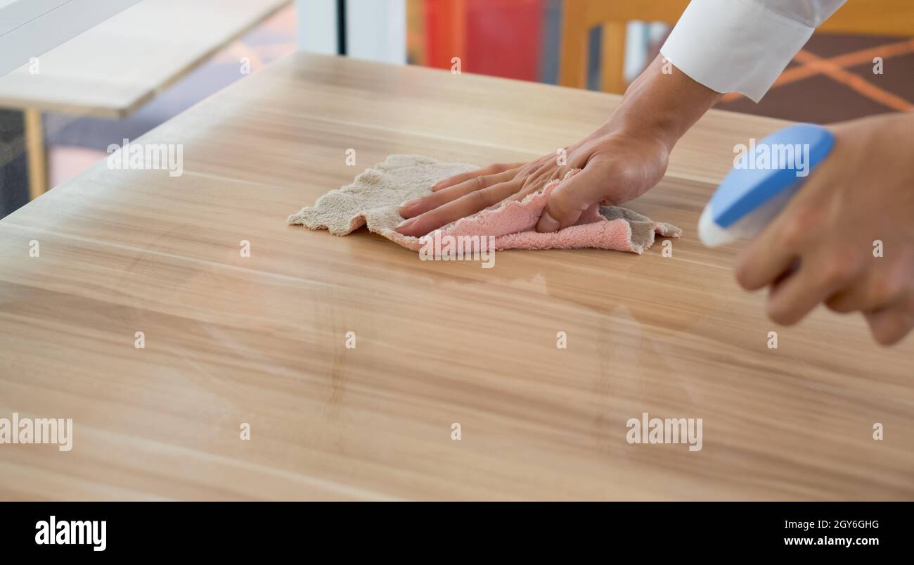 Closeup waiter's hand use a liquid cleaner and a towel to wipe off the ...