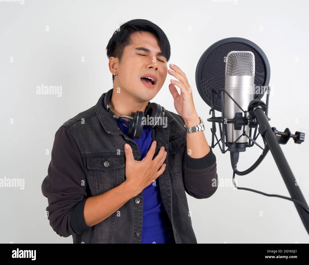 Young asian man with headphones singing with microphone. Portrait on ...