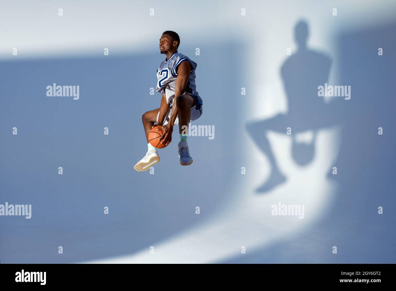 Basketball player with ball shows his skill in studio, high jump in ...