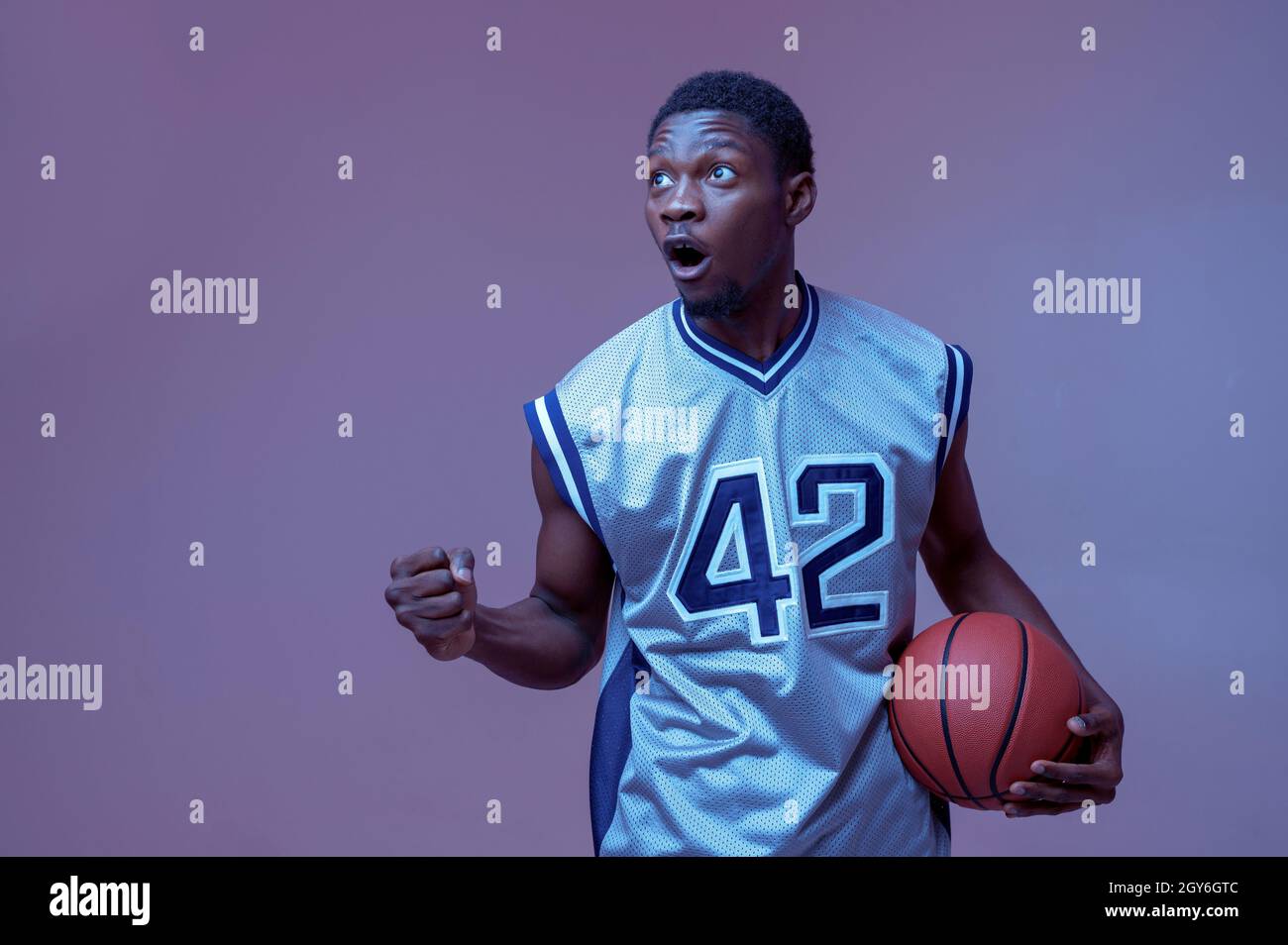 Confident basketball player poses with ball in studio, neon background ...