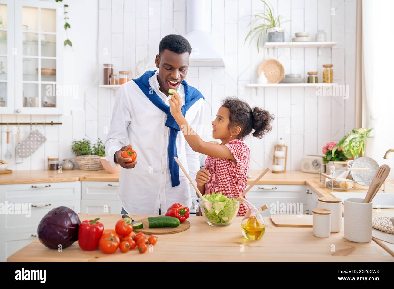Happy dad and kid cooking vegetable salad on breakfast. Smiling family ...