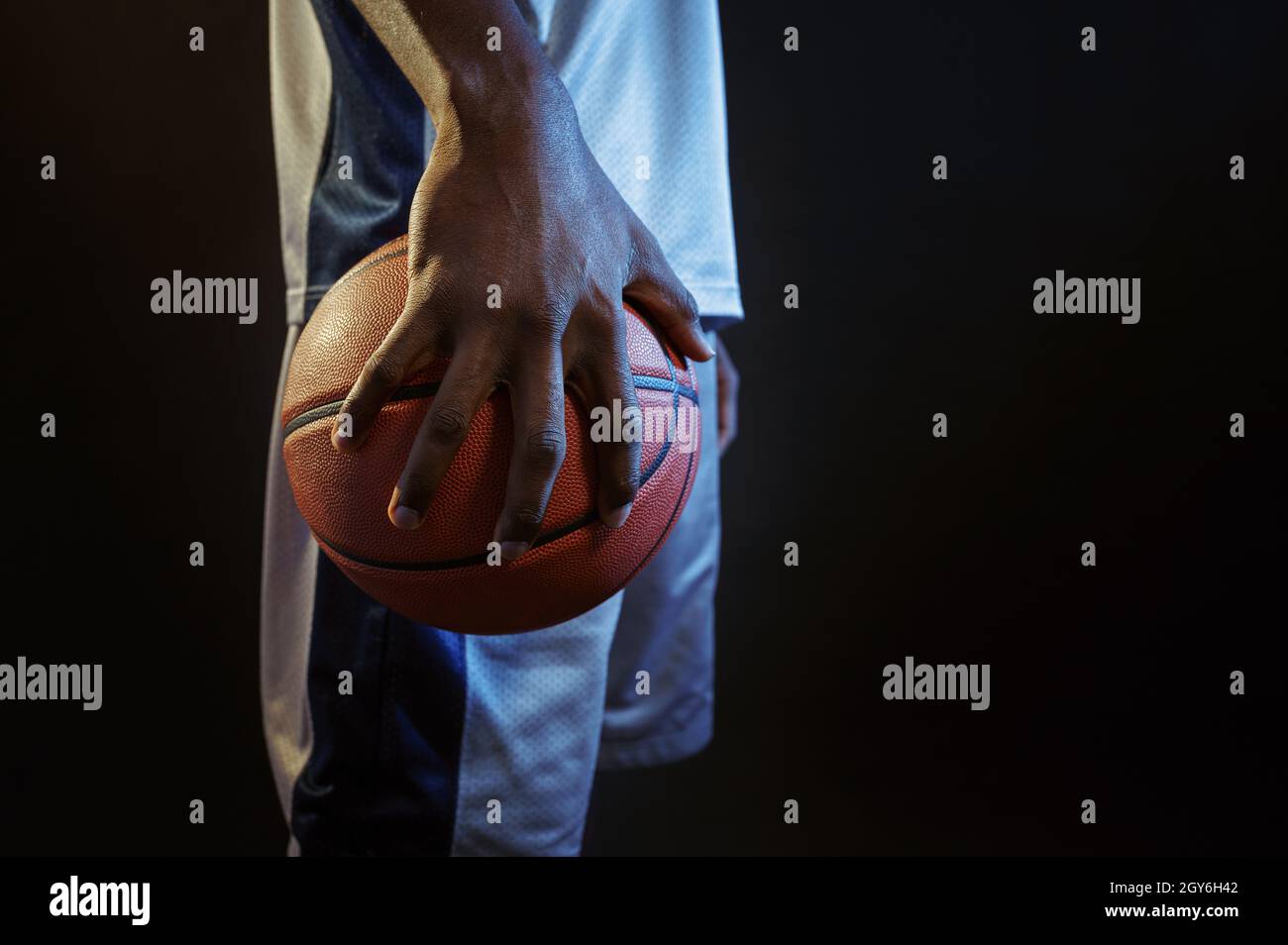 Strong basketball player hand holds ball in studio, black background ...