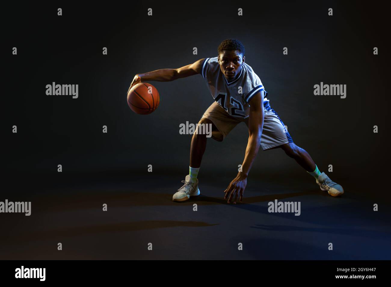 Basketball player with ball, practicing in action in studio, black ...