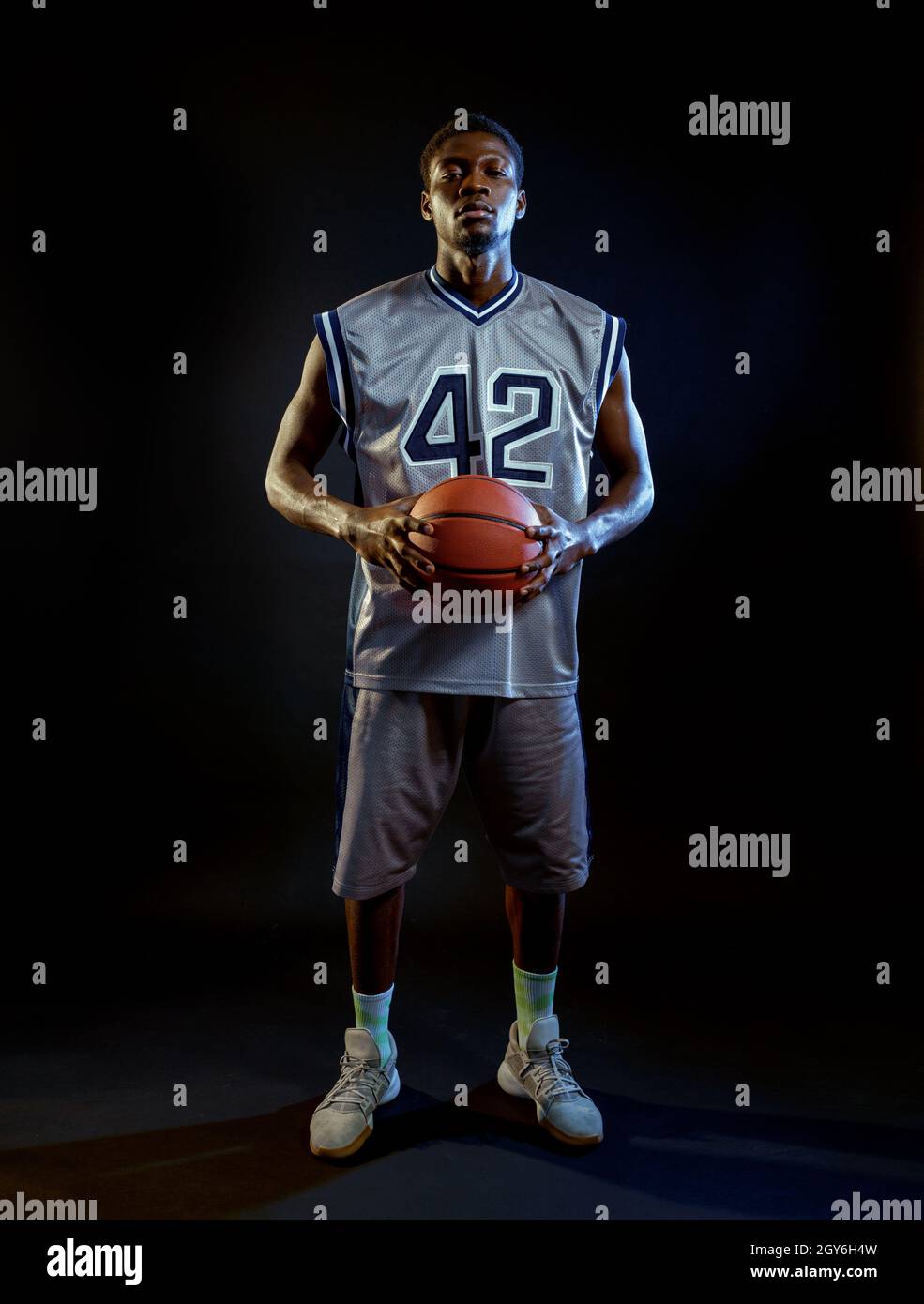 Focused basketball player holds ball in studio, black background ...