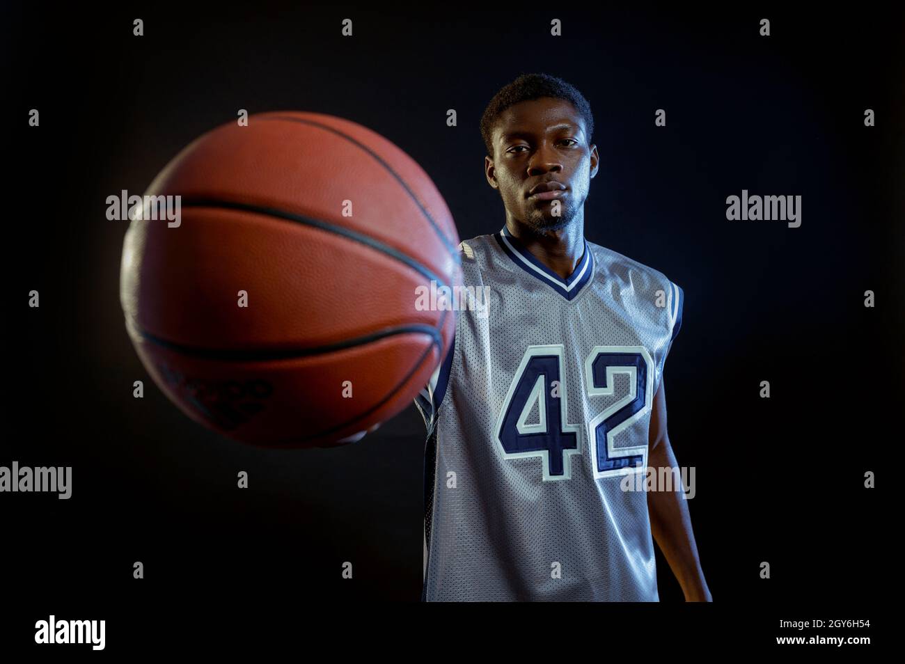 Basketball player shows a ball in studio, black background ...
