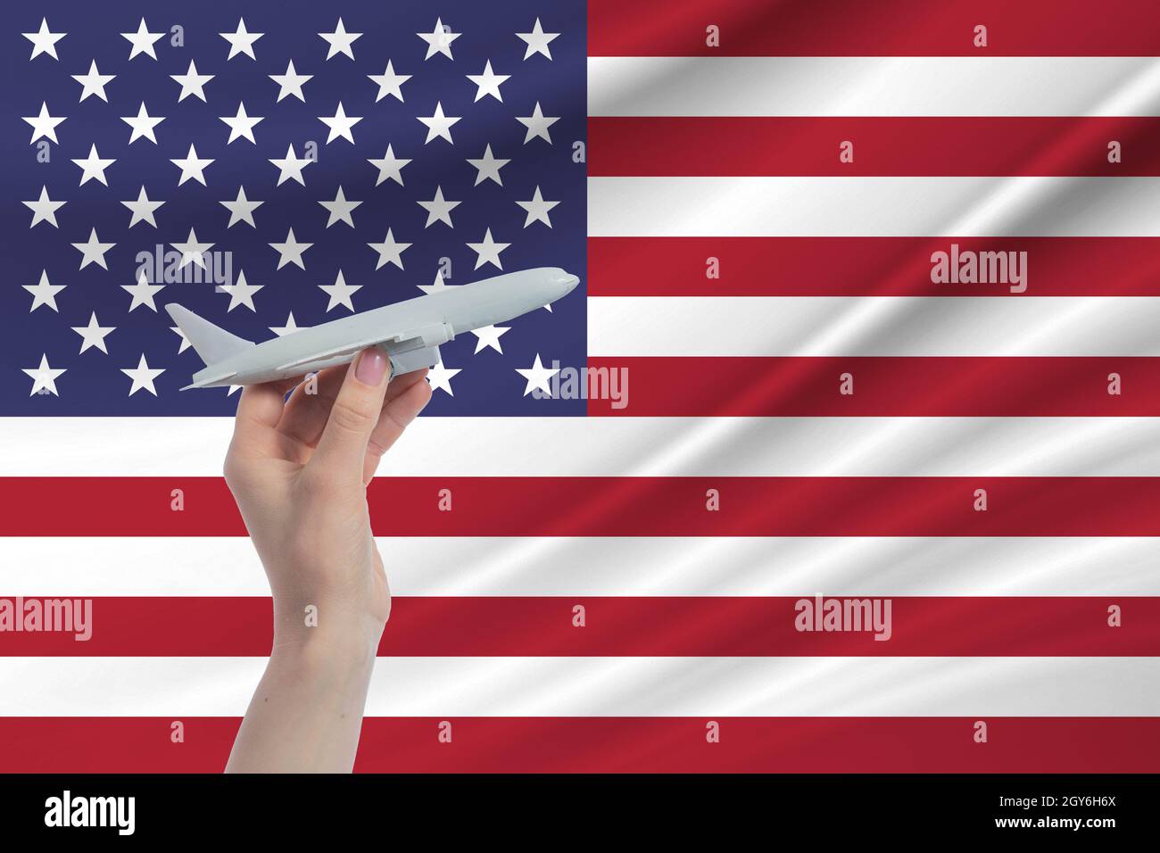 Airplane in hand with national flag of United States. Travel to United ...