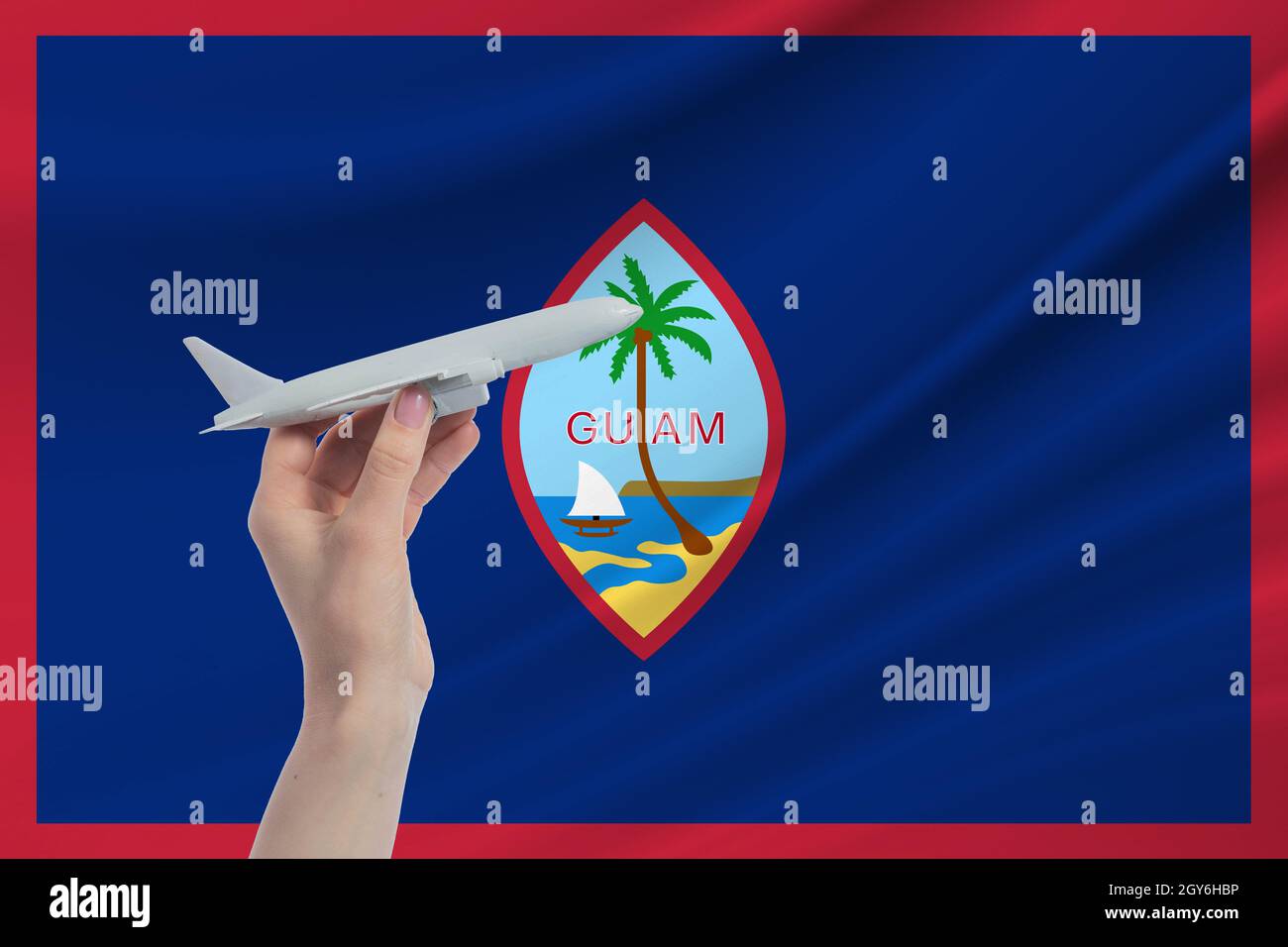 Airplane in hand with national flag of Guam. Travel to Guam Stock Photo ...
