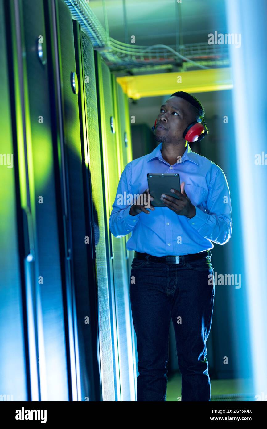 African american male computer technician wearing headphones using ...