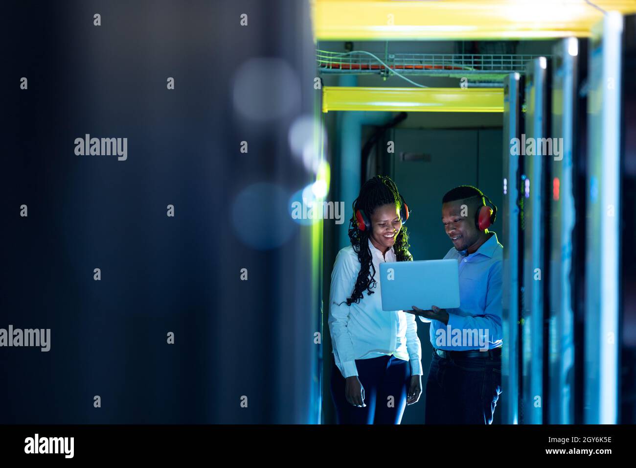African american computer technicians wearing headphones using laptop ...