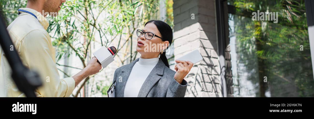 reporter with microphone making reportage with asian businesswoman in ...