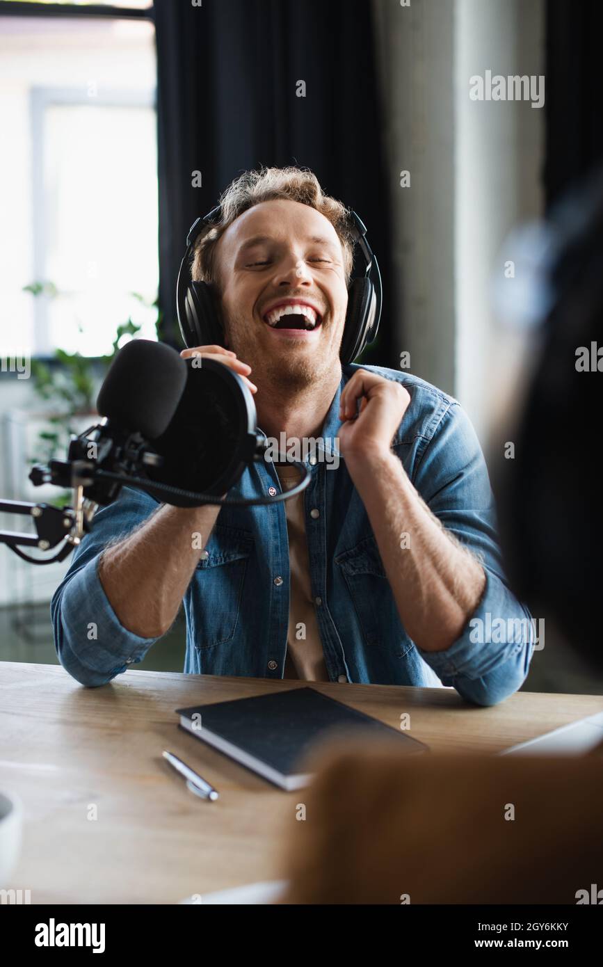 joyful radio host laughing near microphone in studio Stock Photo - Alamy
