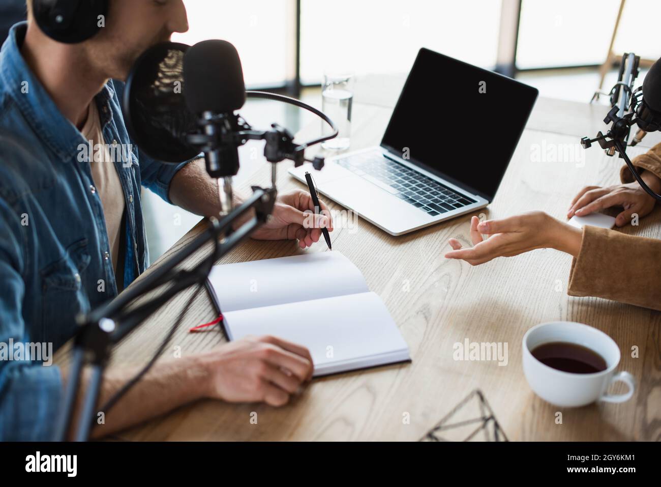 cropped view of radio host pointing at notebook near colleague in ...
