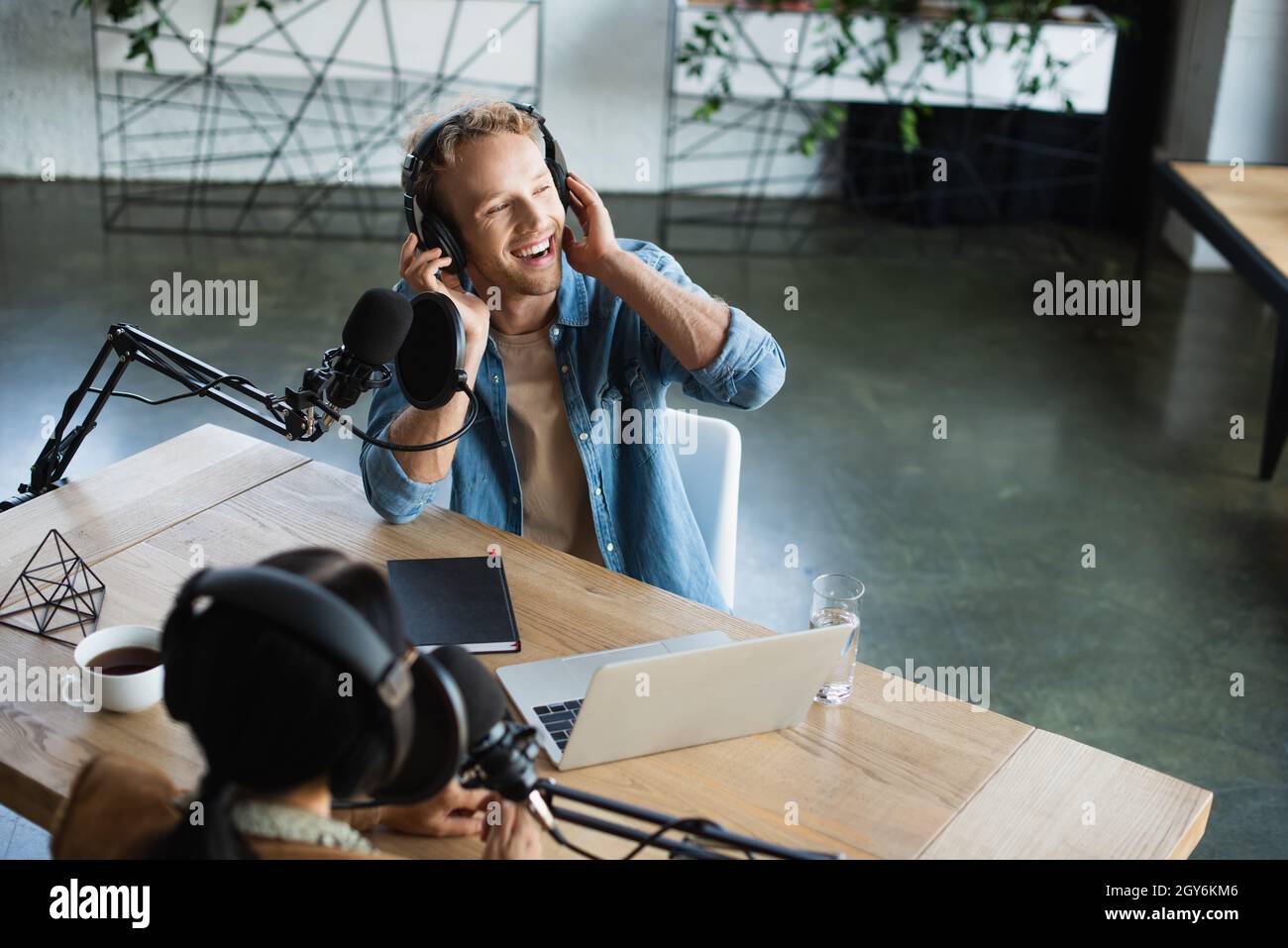 happy radio host adjusting headphones near microphone in studio Stock ...