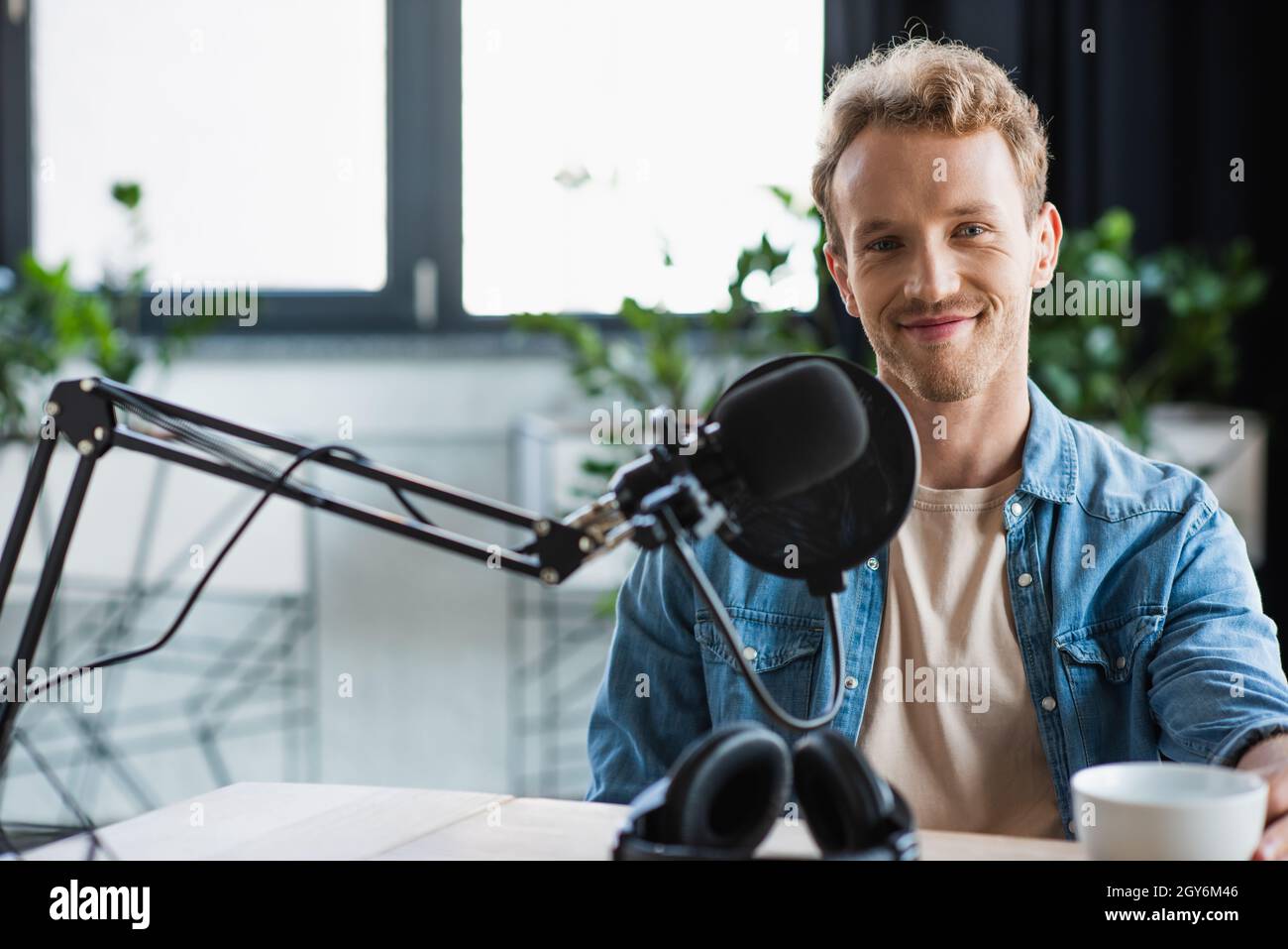 happy influencer looking at camera near microphone in studio Stock ...