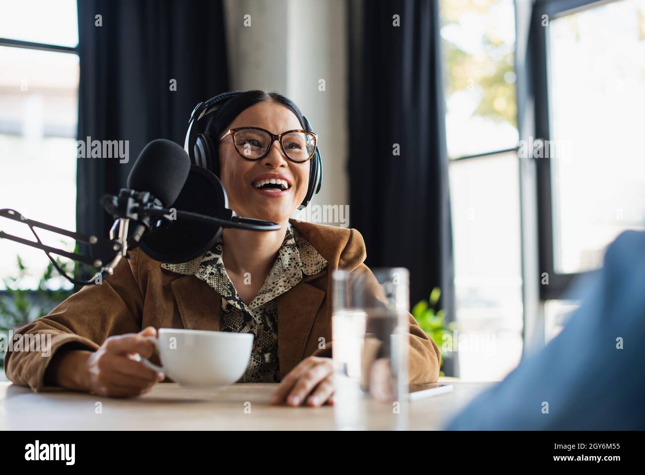 happy asian radio host in eyeglasses and headphones laughing while ...