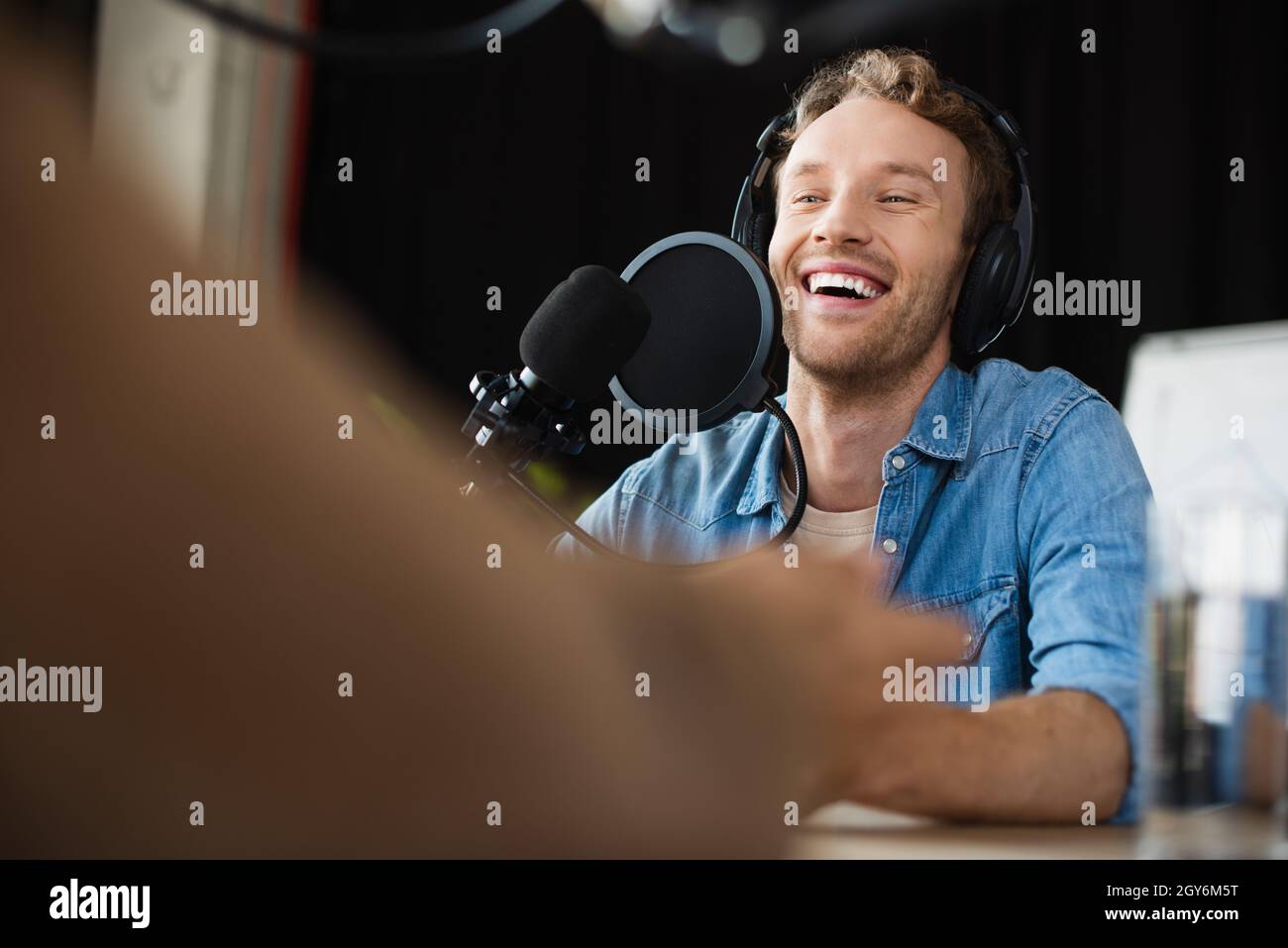 positive radio host in headphones laughing in studio Stock Photo - Alamy