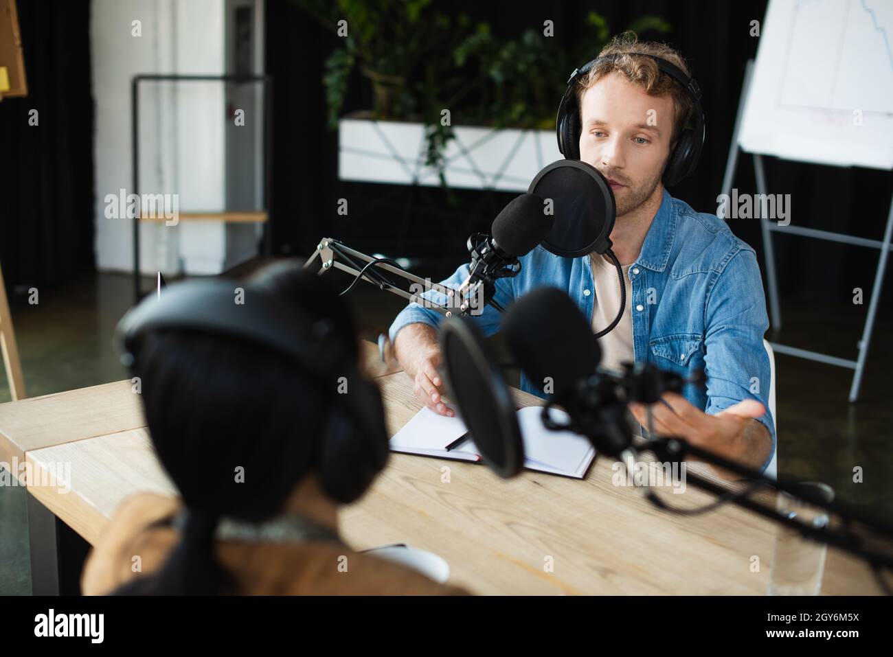 radio host in headphones talking in microphone and looking at blurred ...