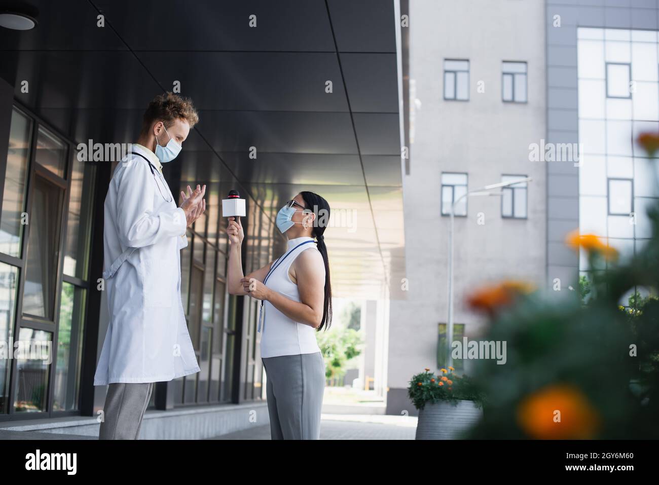 side view of asian journalist with microphone taking interview of ...