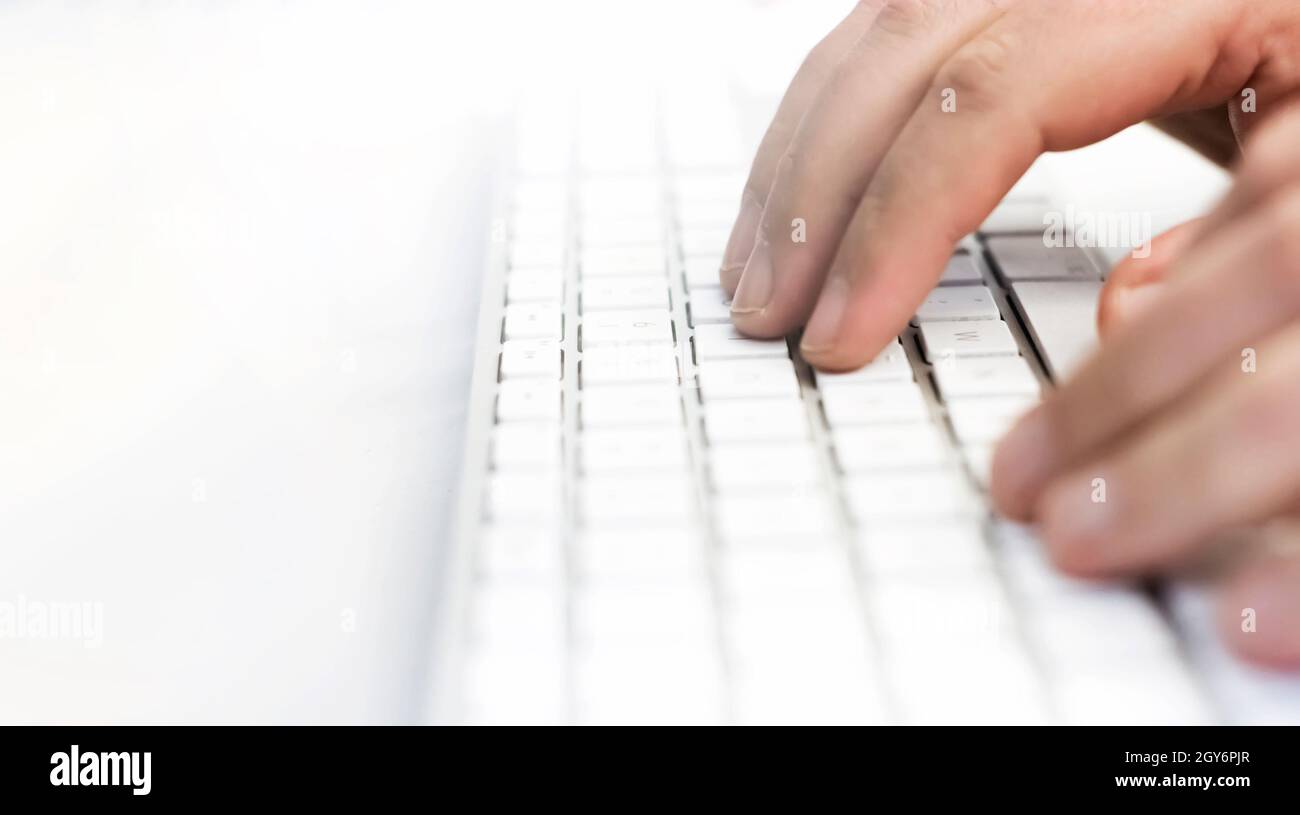 a male hand over the white keyboard of a computer before typing. Work ...