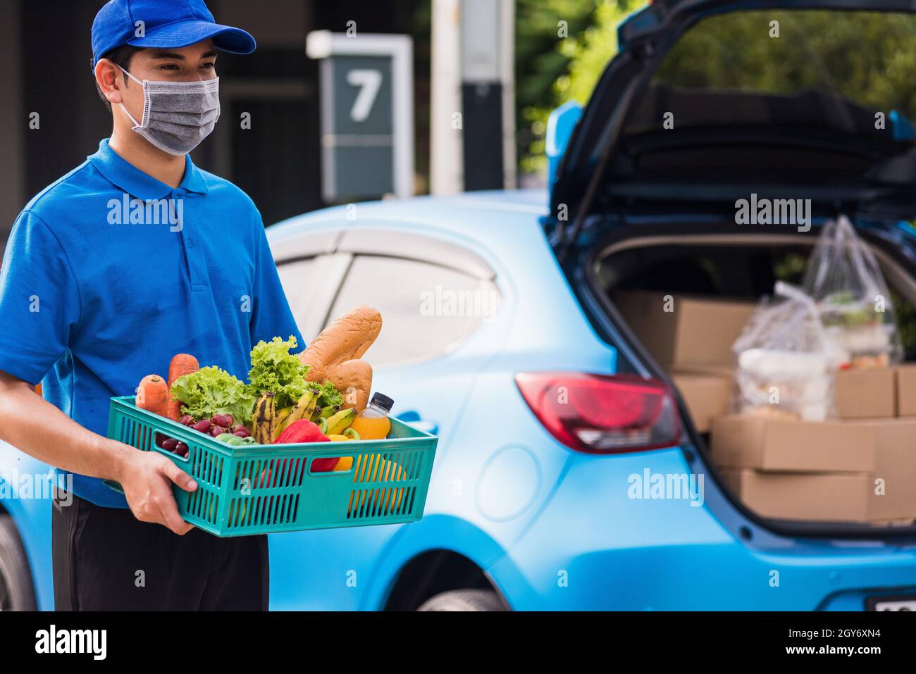 Asian grocery store delivery man wearing blue uniform and face mask ...