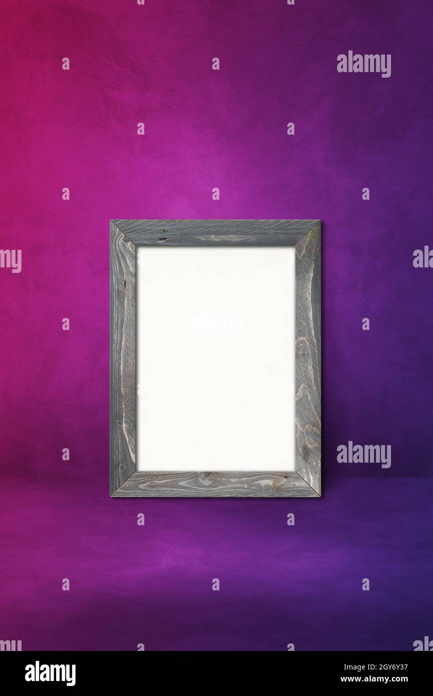 Wooden picture frame leaning on a purple wall. Blank mockup template ...