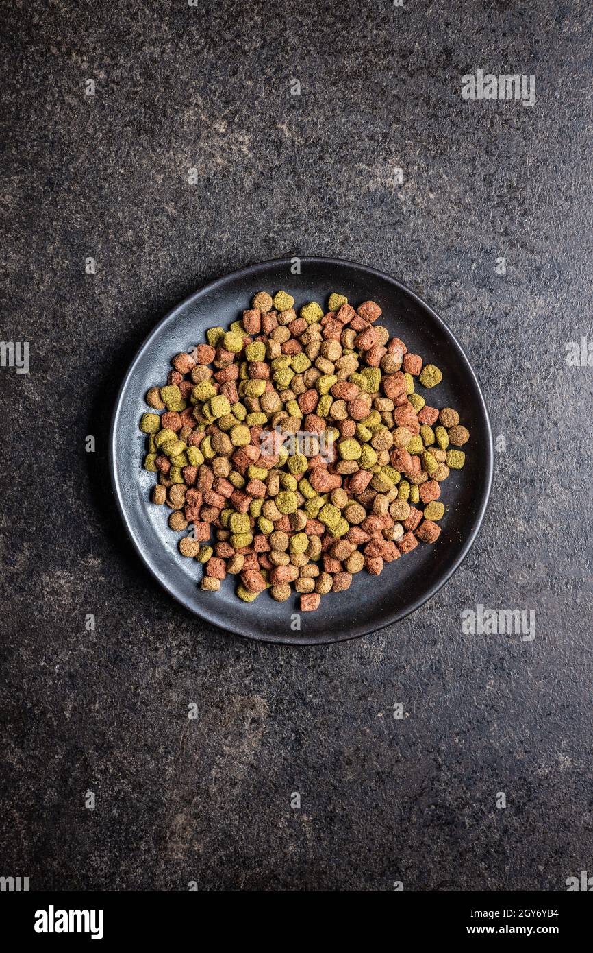 Dry kibble animal food. Dried food for cats or dogs on black table. Top ...