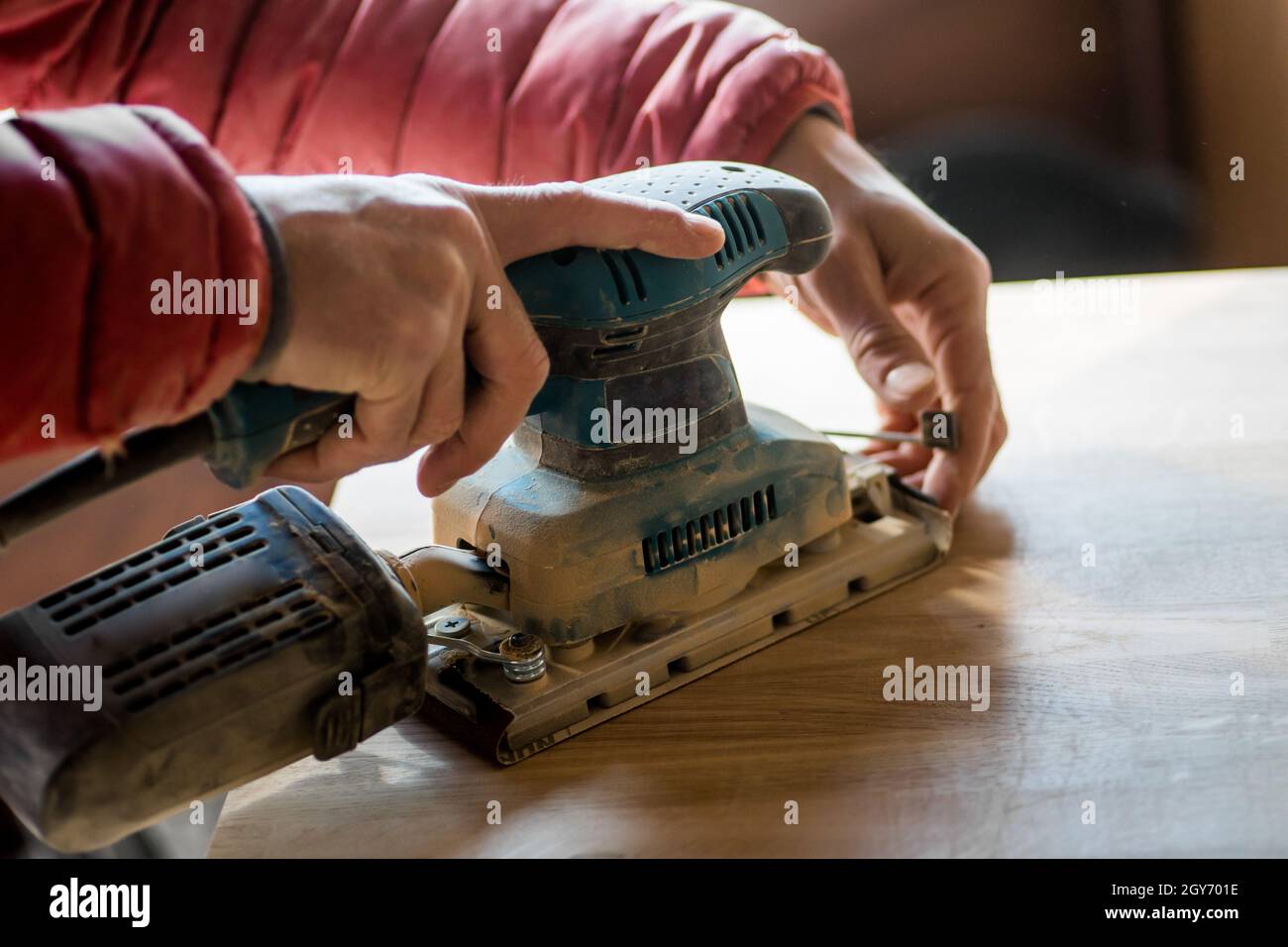 Man sanding wood plank using electric sand machine Stock Photo - Alamy