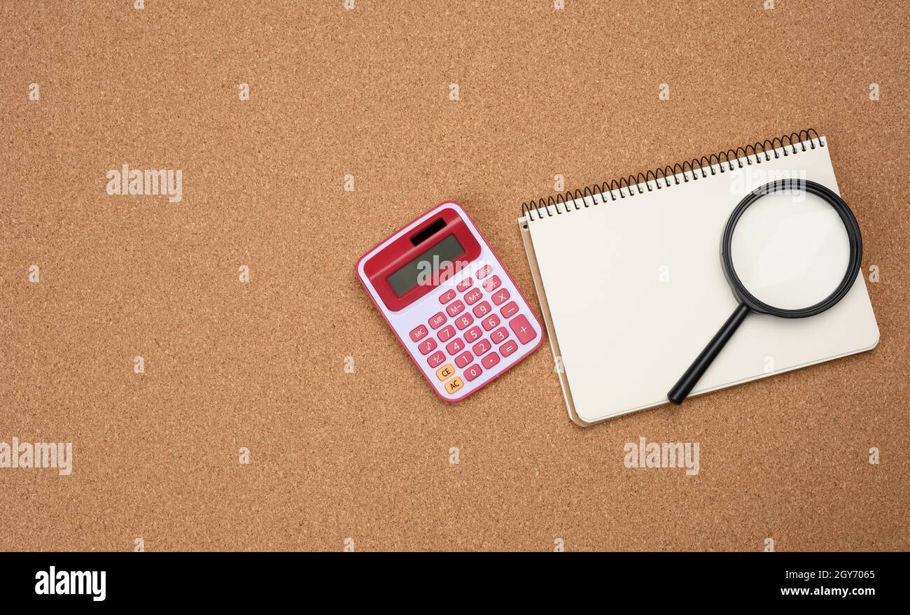 pink calculator, notebook with blank white sheets and black magnifier ...
