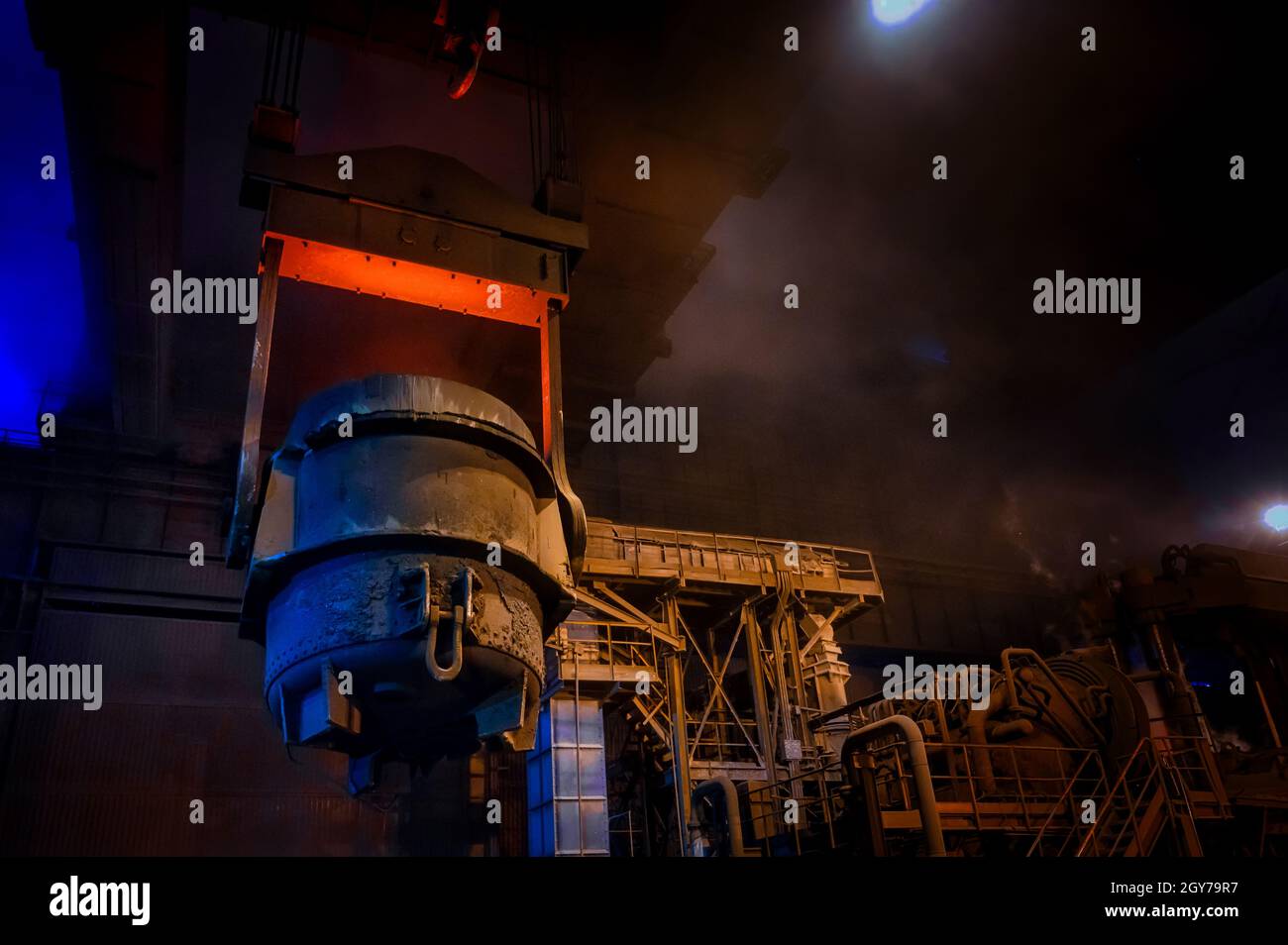 A metallurgical ladle filled with molten metal bucket is suspended on a ...