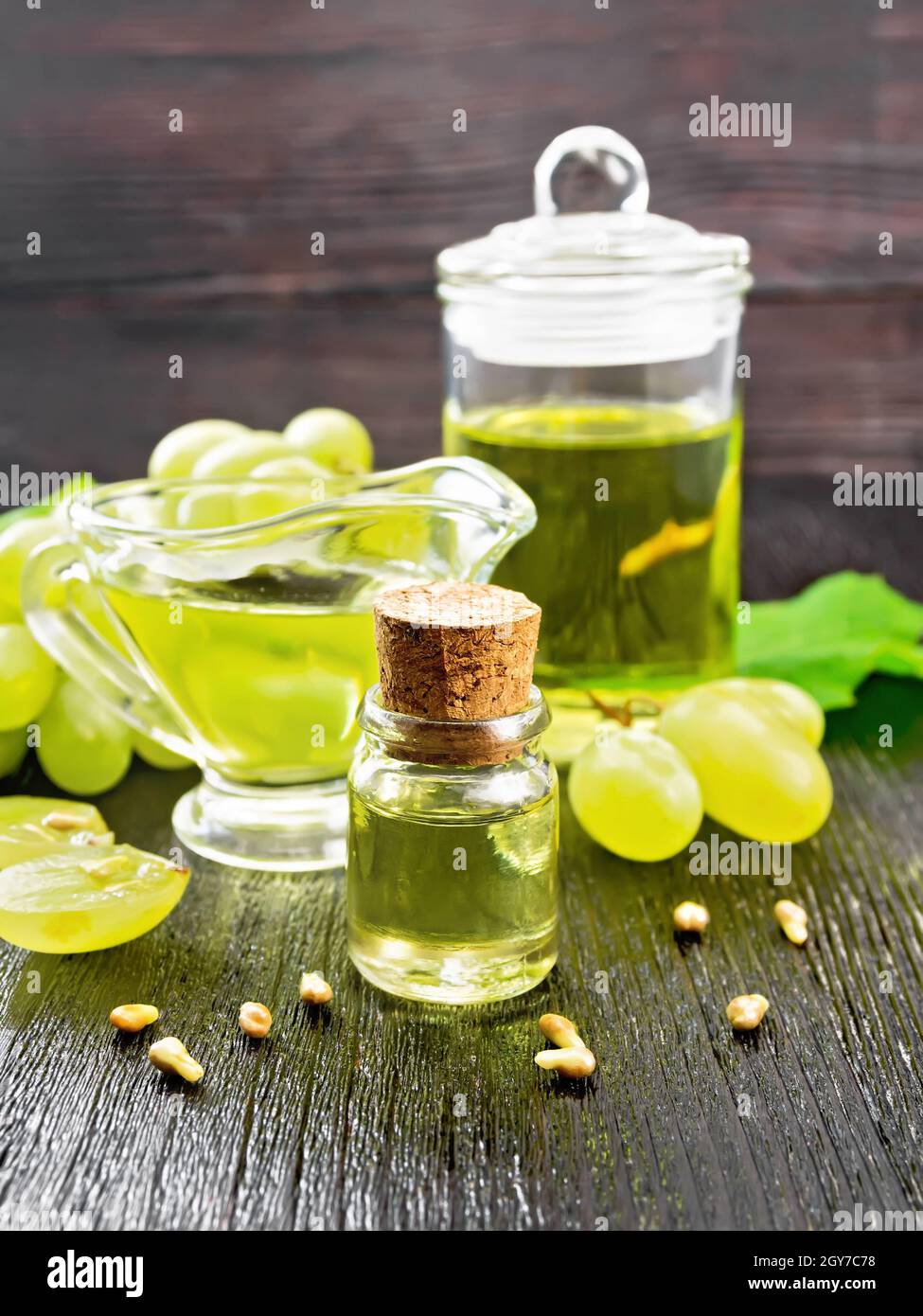 Grape oil in a bottle, gravy boat and jar, berries of green grapes on ...