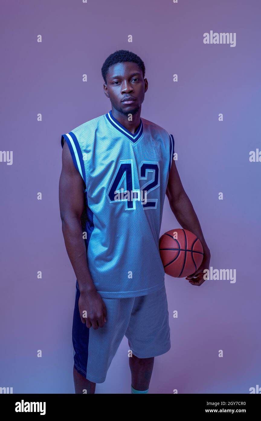 Strong basketball player hand holds ball in studio, neon background ...