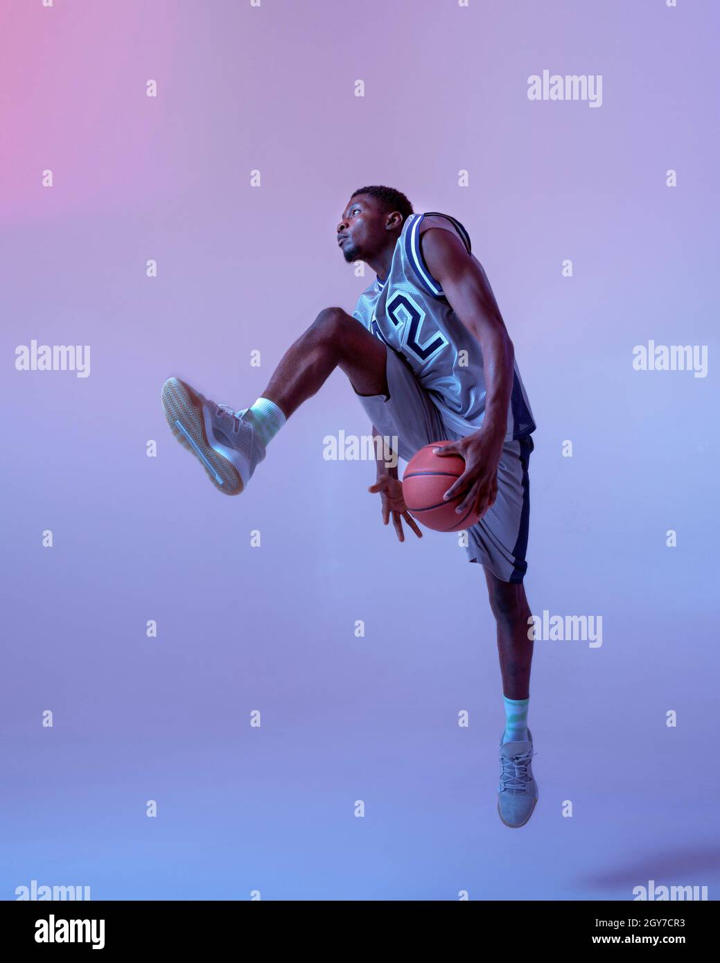 Basketball player moving with ball in studio, neon background ...