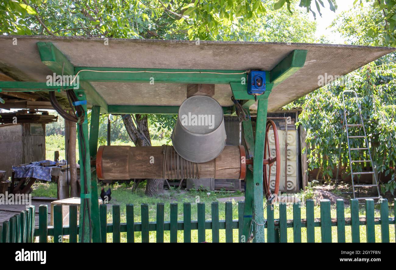 An old water well with a bucket in the garden, a metal handle for ...