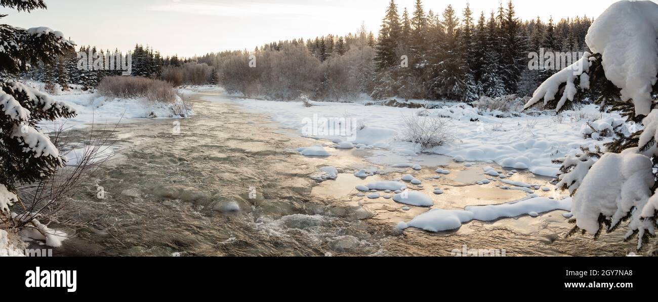 Mountain river freezing on a cold winter morning with fog rising from ...
