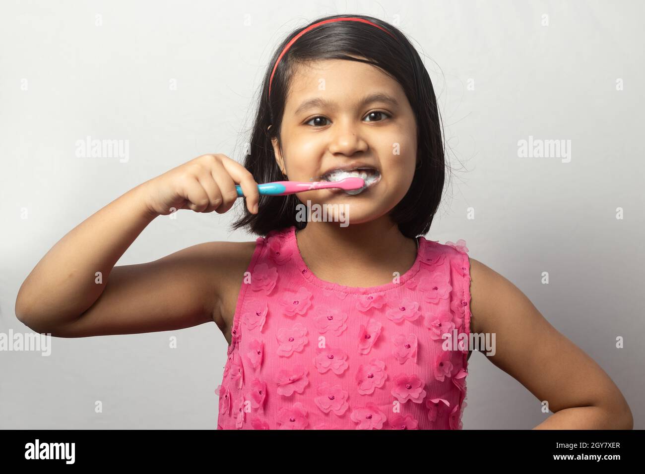 Portrait of an Indian girl child brushing teeth v on white background ...
