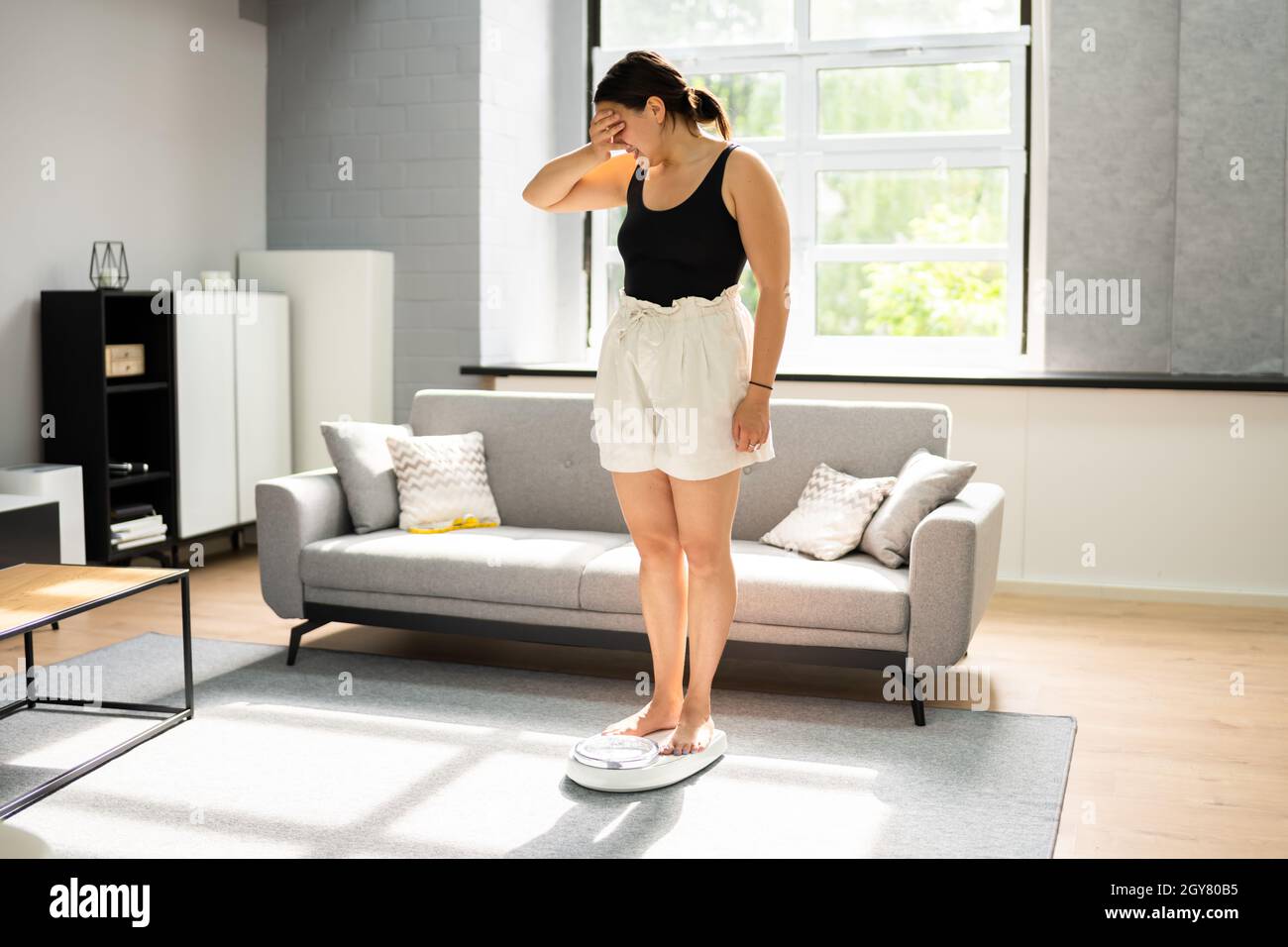 Sad Woman On Weight Scale After Diet Checking Stock Photo - Alamy