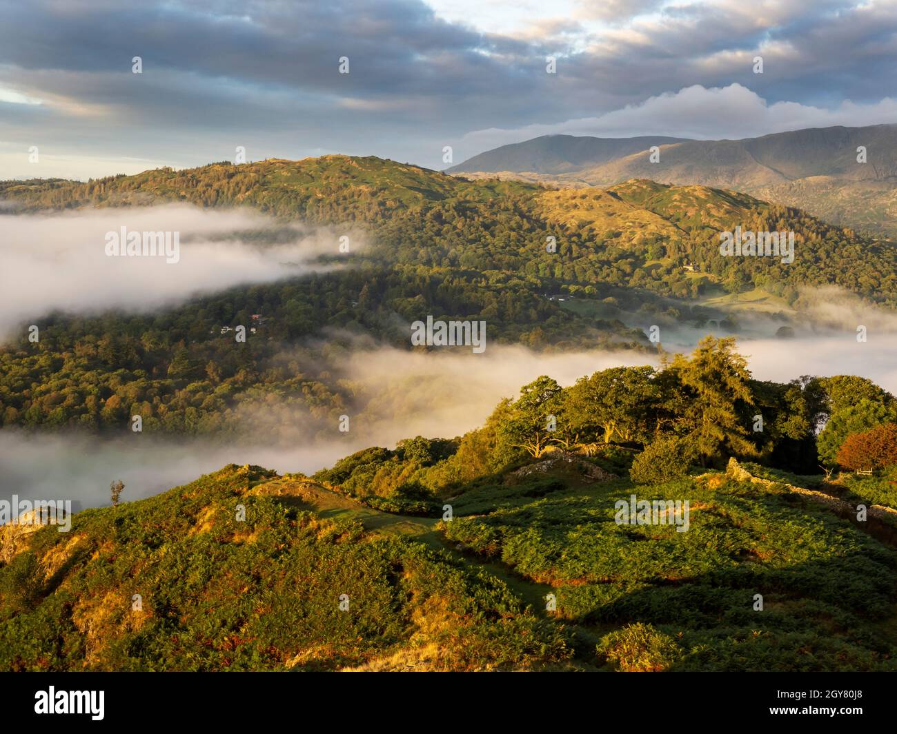 Dawn light over Coniston old Man and Wetherlam, with mist in the ...