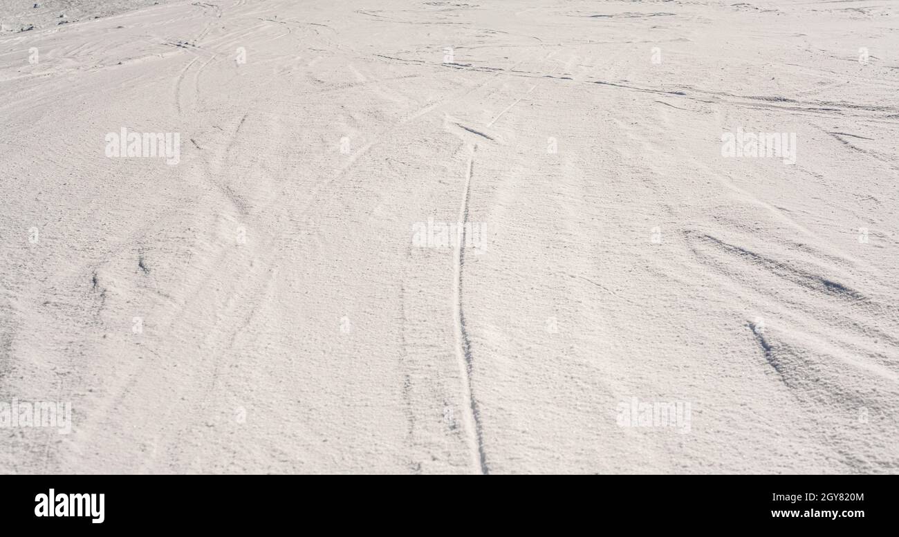 Slope covered with crystalline snow, few trails from ski visible Stock ...