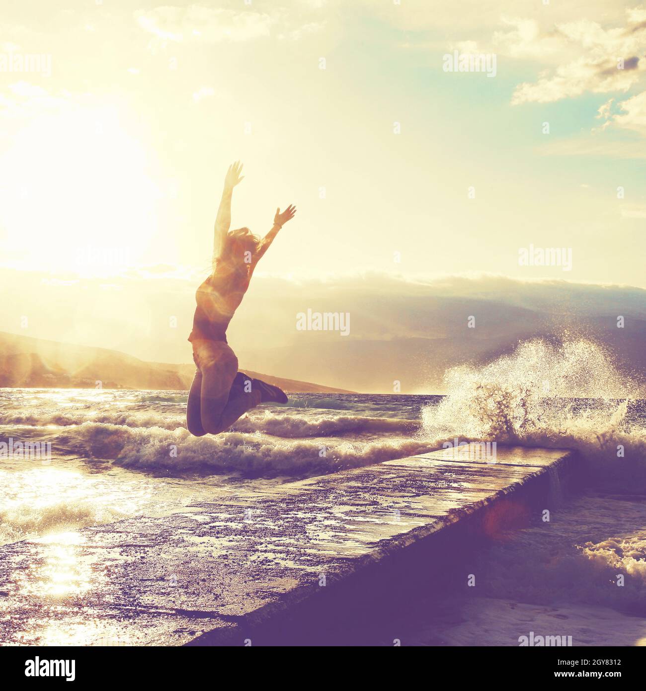 Feeling of freedom concept. Woman jump on pier facing to the sea with ...