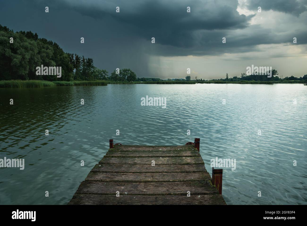 Wooden pier towards the lake and a thundercloud Stock Photo - Alamy