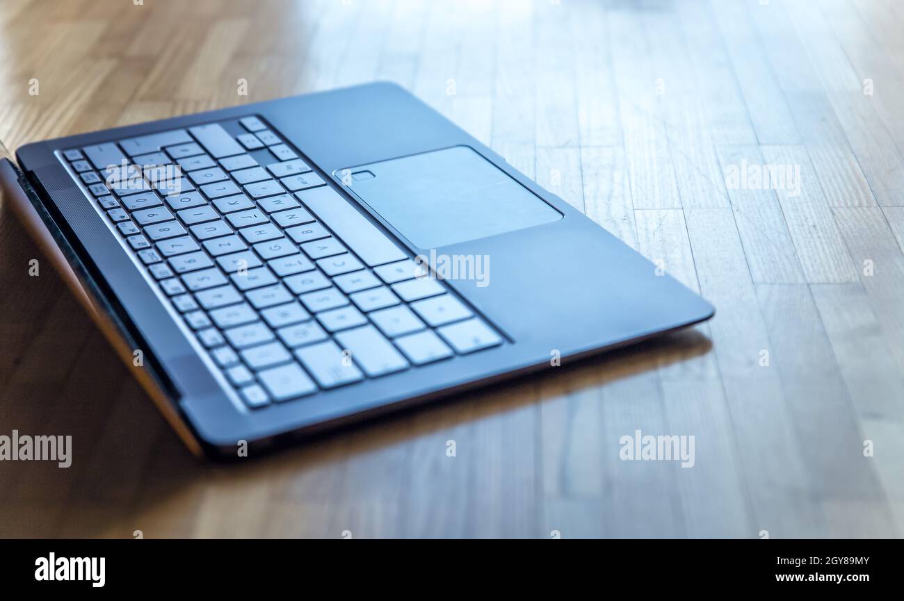 Cutout of a modern laptop keyboard on the wooden floor with text space ...