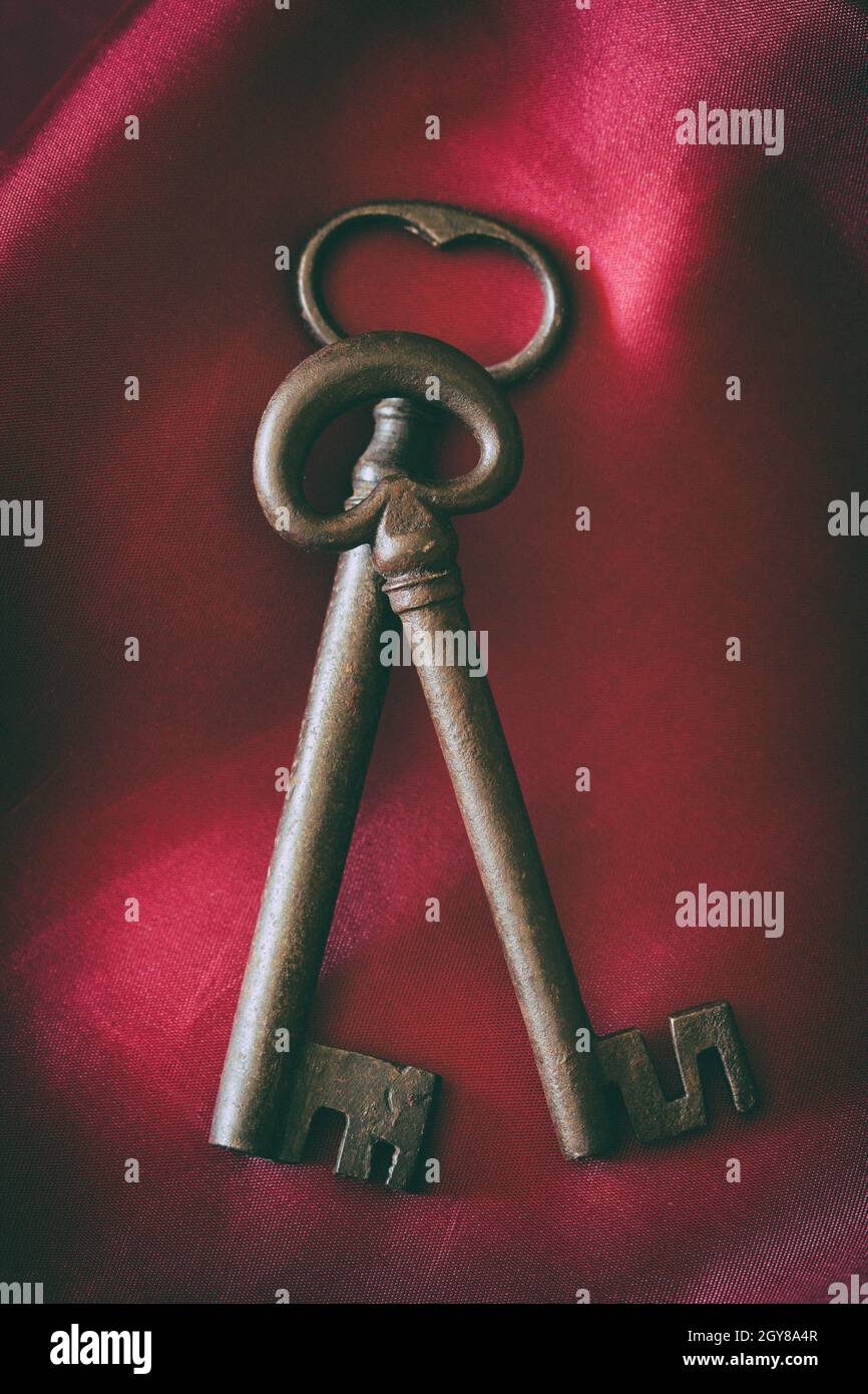 Old medieval wrought iron keys on red background Stock Photo - Alamy