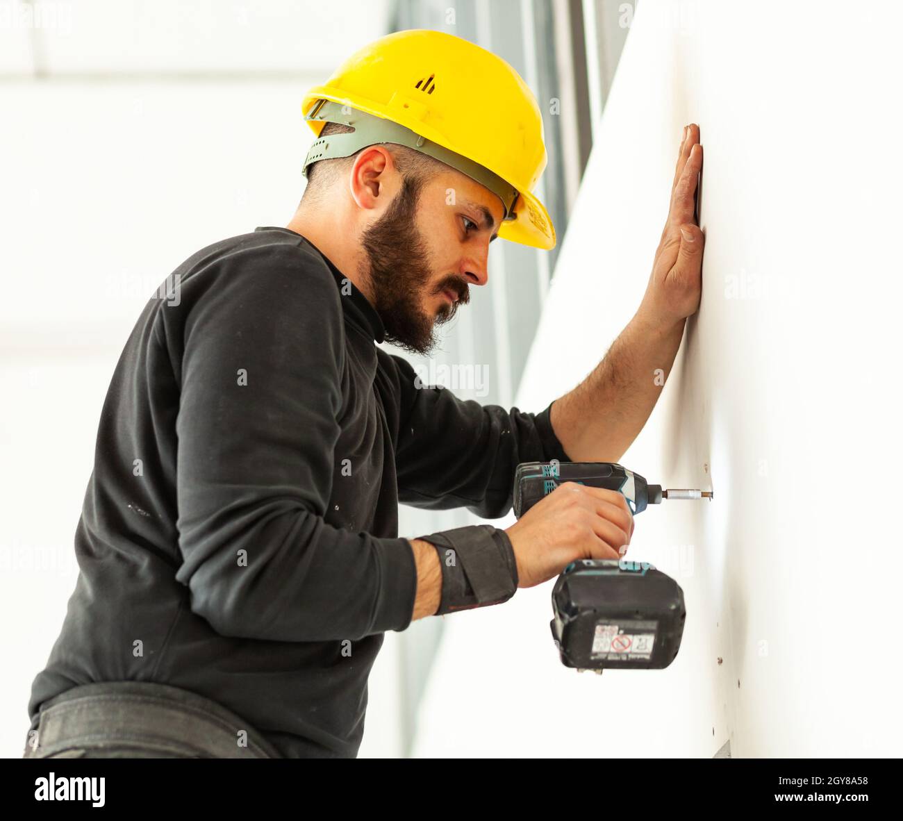 Worker screws plasterboard panels on an aluminum structure Stock Photo ...