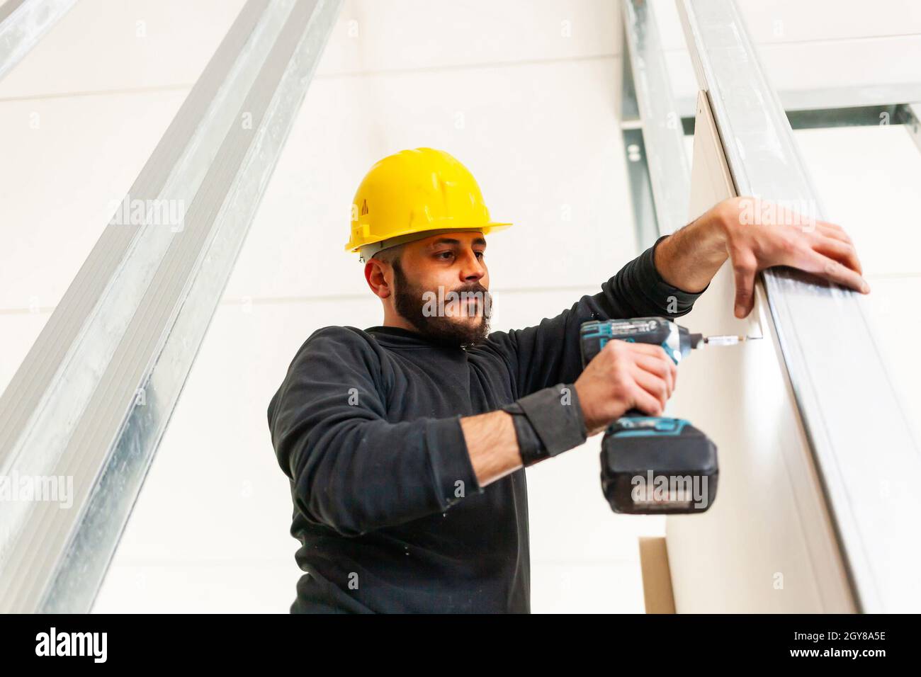 Worker screws plasterboard panels on an aluminum structure Stock Photo ...