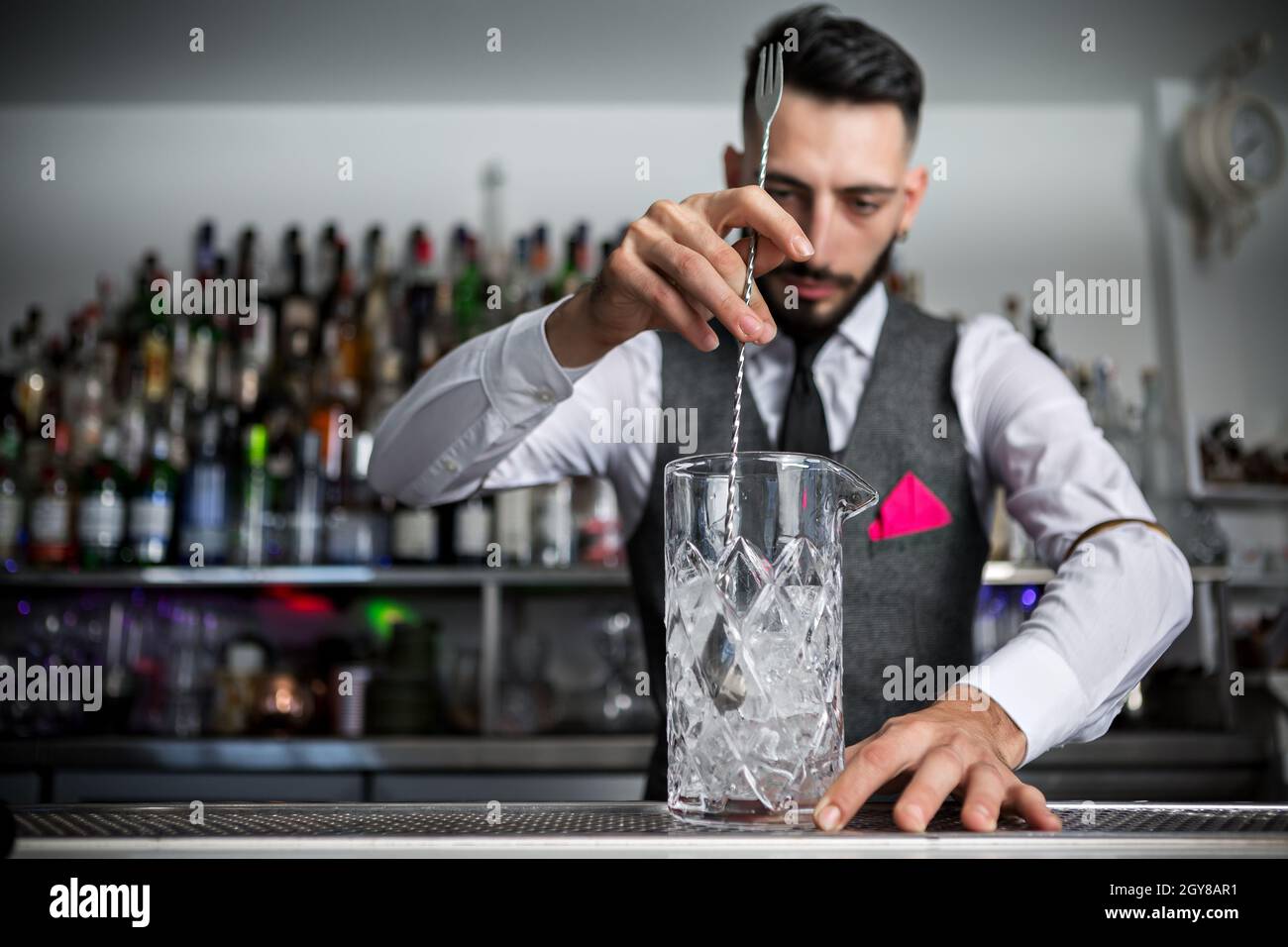 Professional barman stirring alcohol cocktail with long spoon in mixing ...