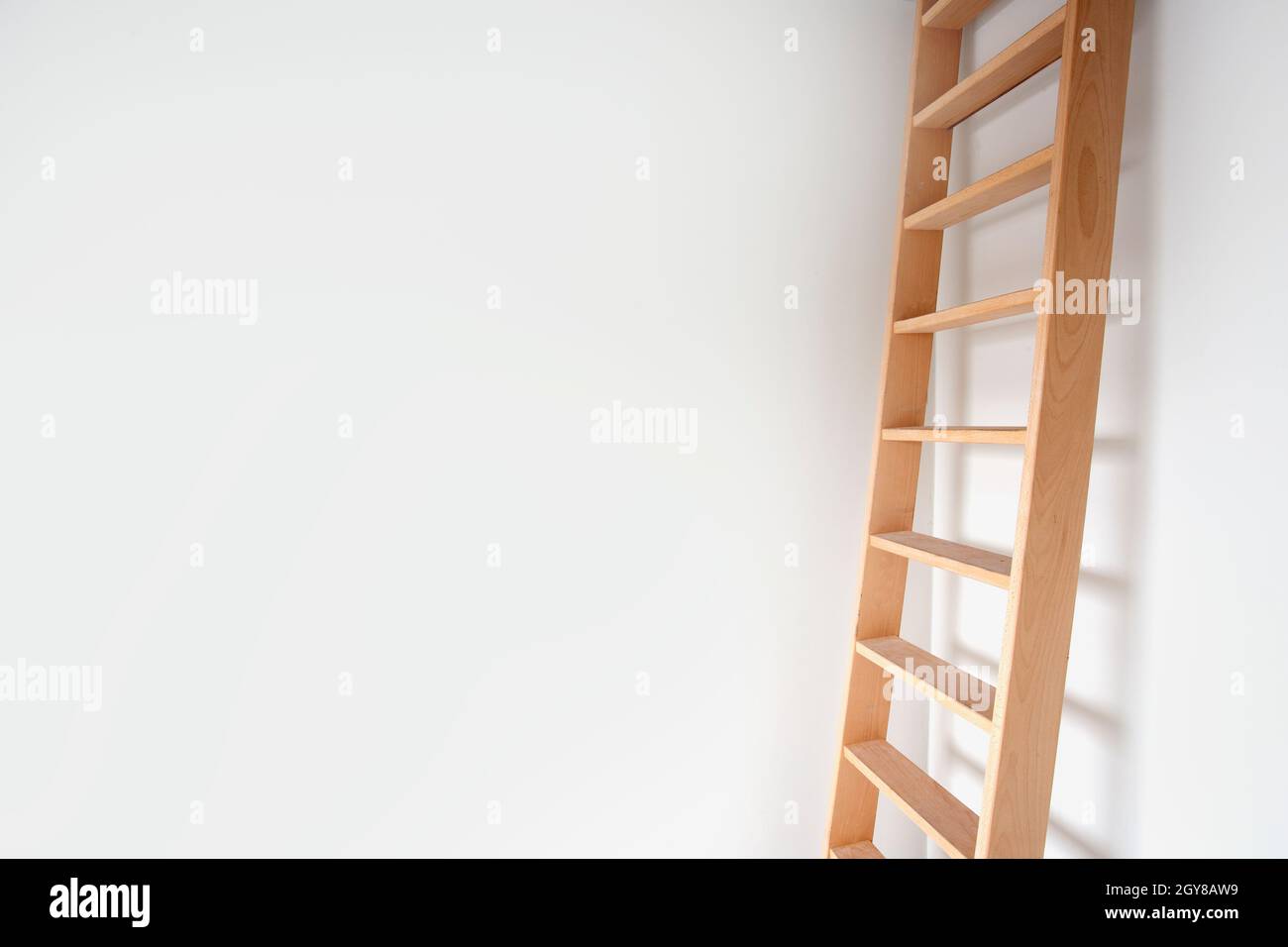 Sideview of a wooden ladder leaning against white wall modern design ...