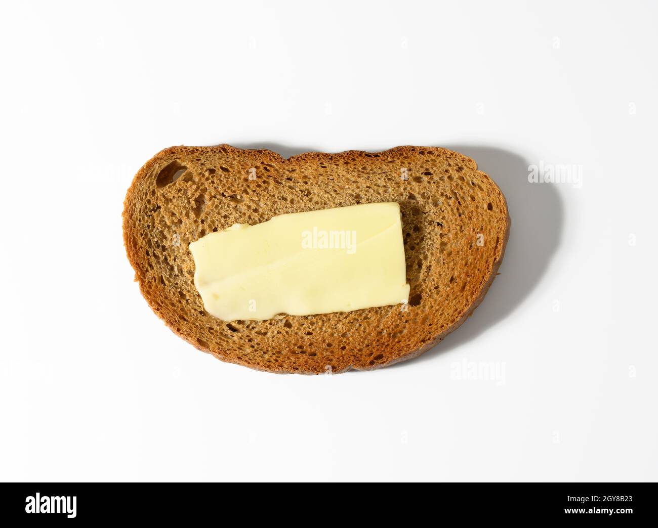 oval slice of rye flour bread, a slice of butter on top, white ...