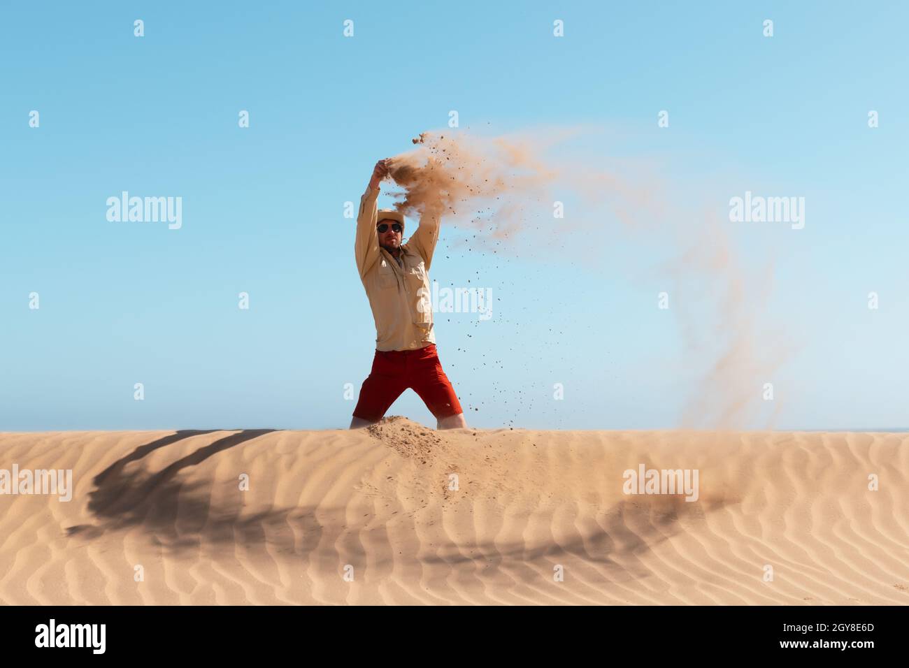 Single man throws sand in the Namib desert at sunrise on blue sky ...