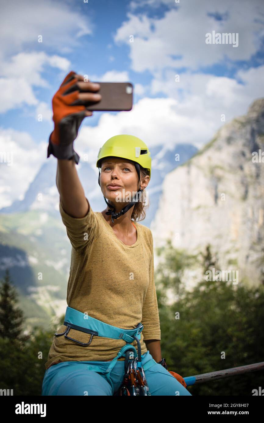Pretty, female climber on a via ferrata - climbing on a rock in Swiss ...