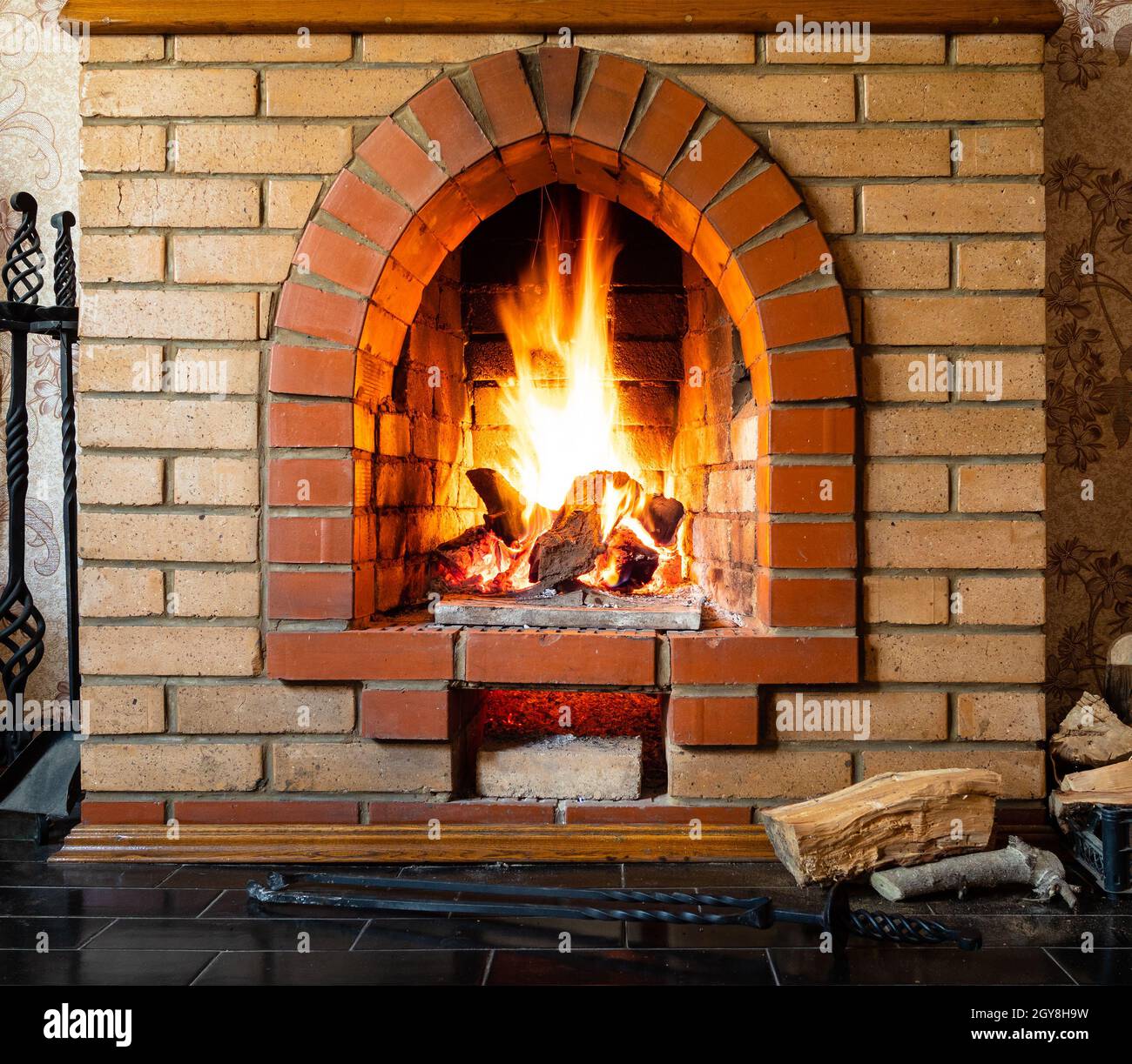 front view of brick fireplace with mantelpiece and burning woods in ...